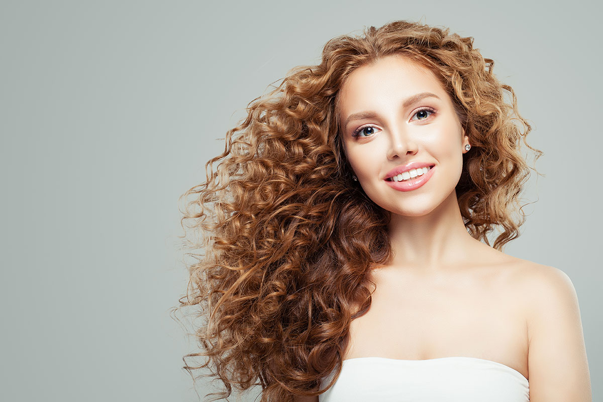 Capelli ricci castano ramato, spostati quasi interamente di lato